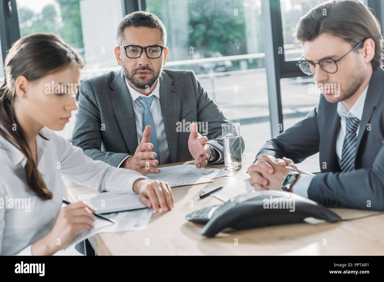 confident business people having conversation and using speakerphone at ...
