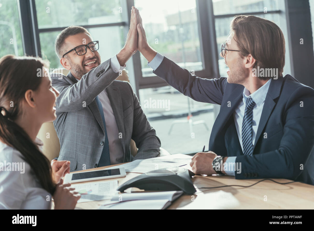 happy business people giving high five during meeting at modern office ...