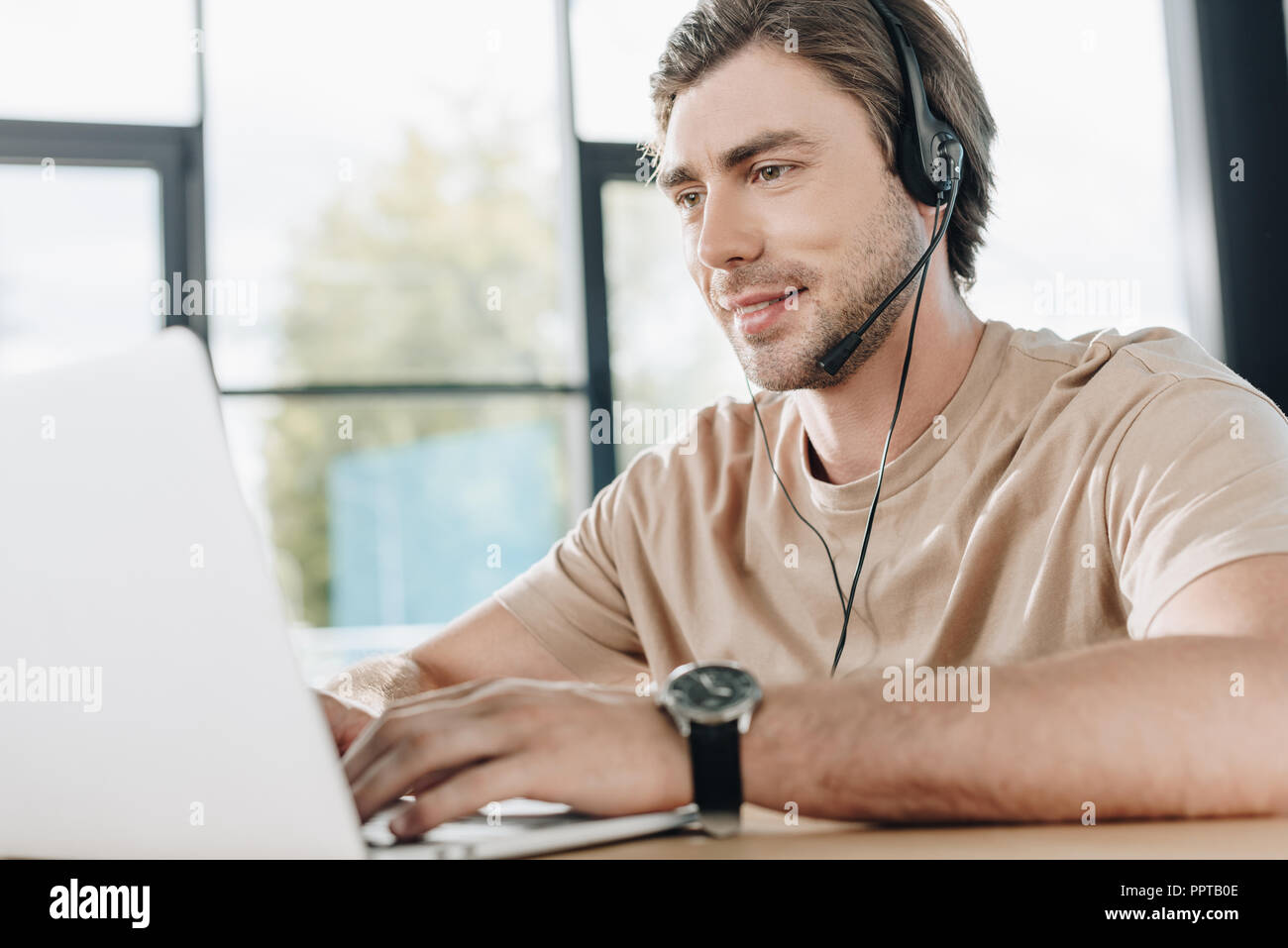 smiling young support hotline worker with laptop and headphones at ...