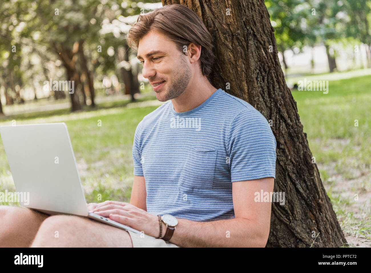 Man sitting by tree using laptop hi-res stock photography and images ...
