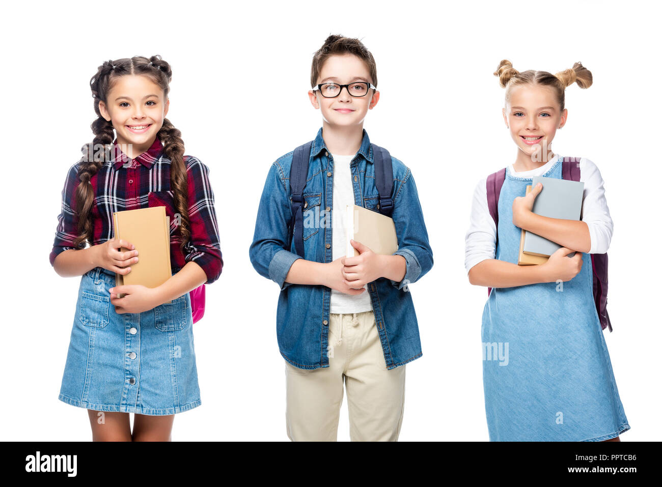 three smiling classmates holding books and looking at camera isolated ...