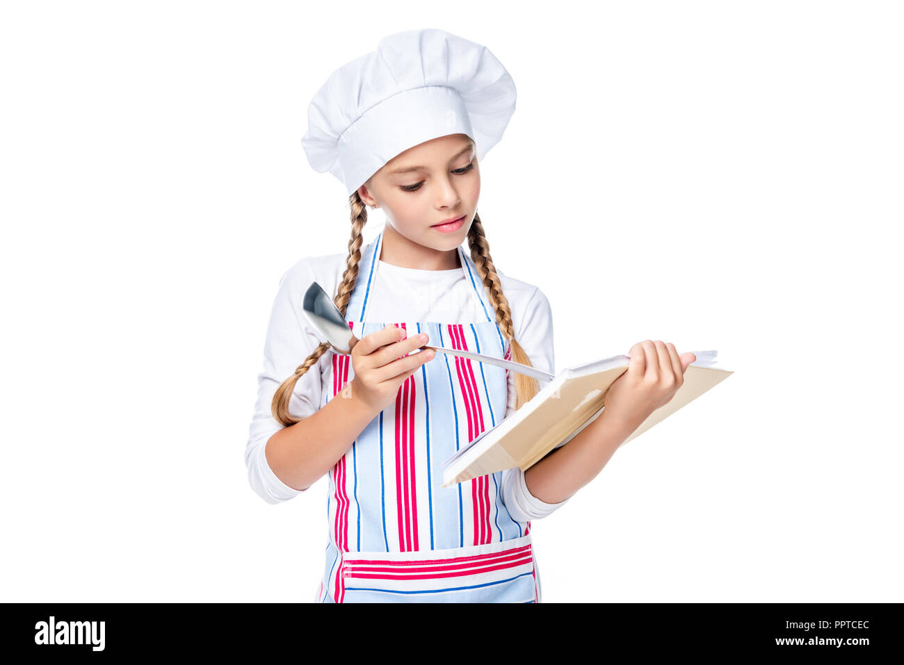 schoolchild in costume of chef reading recipe book isolated on white ...