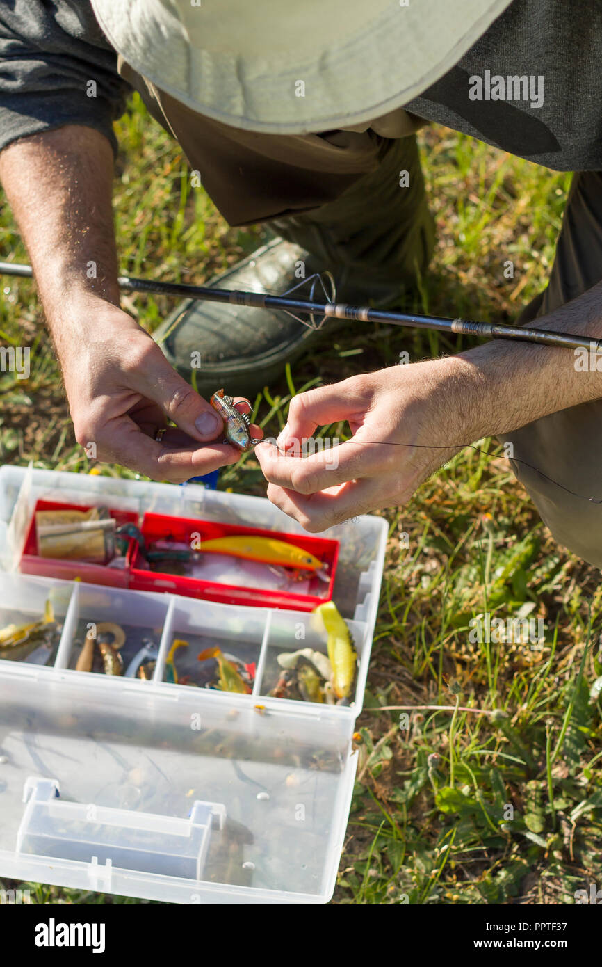An angler's rod chooses a spinning bait from the box. The fisherman ...
