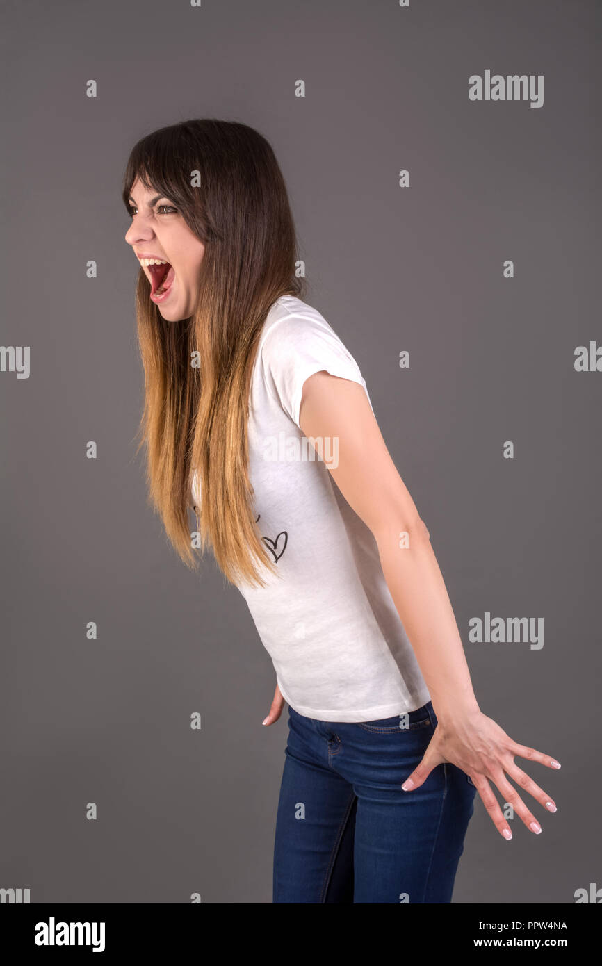 A young woman is shouting loudly. The girl screaming with wild open ...