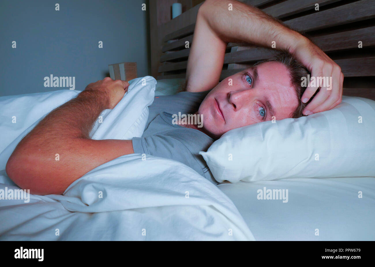 restless worried young attractive man awake at night lying on bed ...