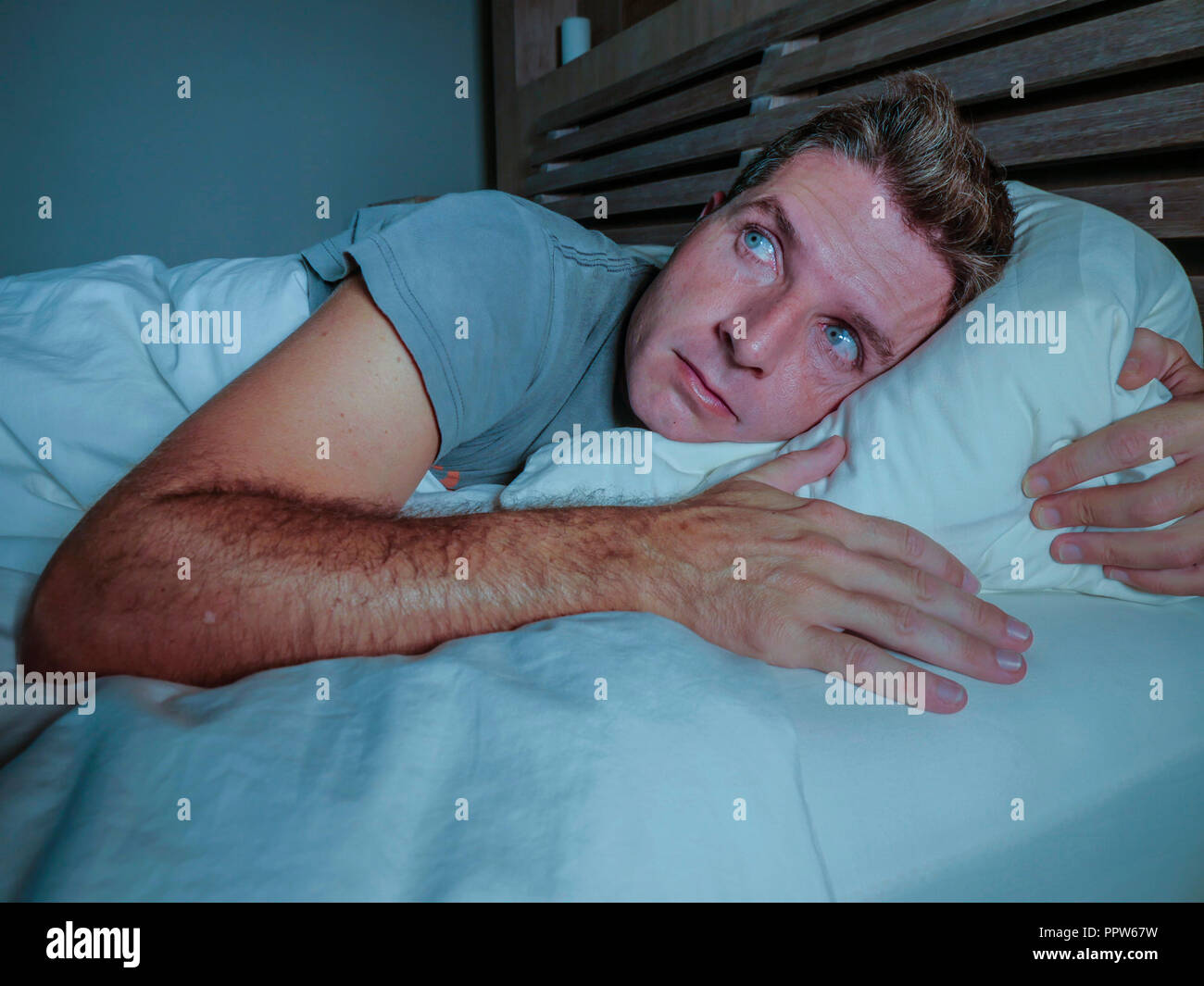 restless worried young attractive man awake at night lying on bed ...