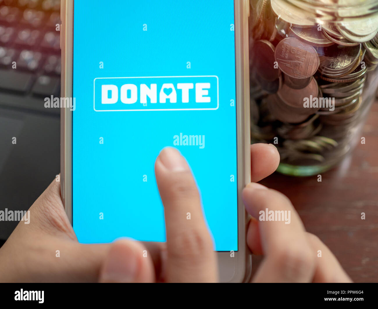 Close-up Finger pressing donate icon button on blue screen on white ...