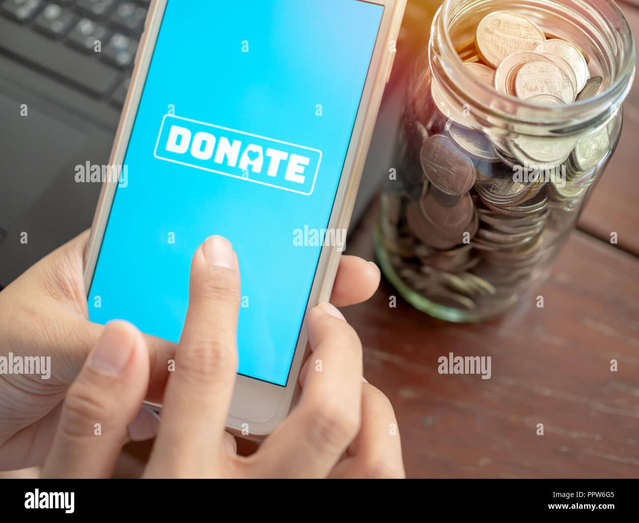 Close-up Finger pressing donate icon button on blue screen on white ...