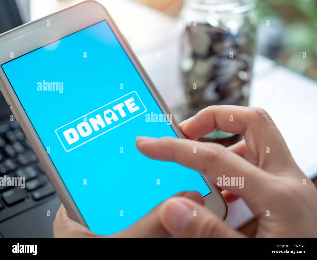 Close-up Finger pressing donate icon button on blue screen on white ...