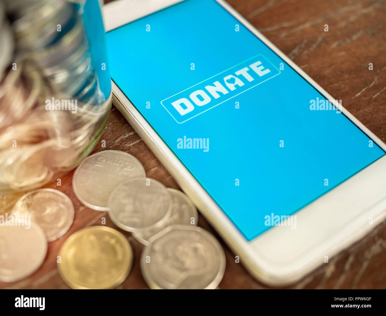 Close-up donate icon button on blue screen on white mobile phone with ...