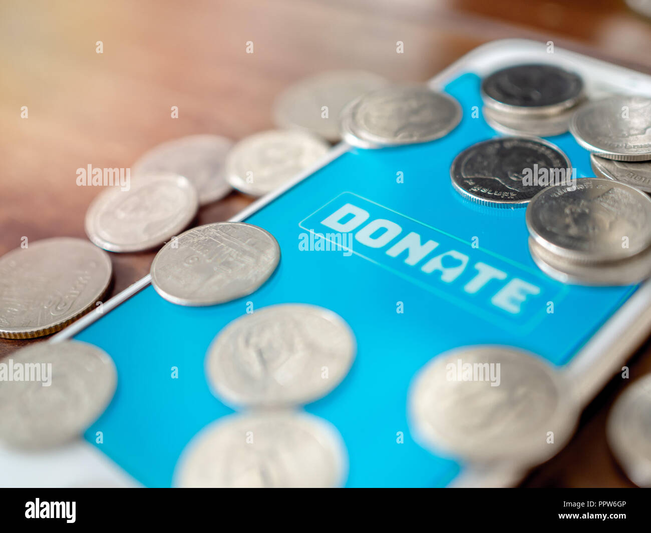 Close-up donate icon button on blue screen on white mobile phone with ...