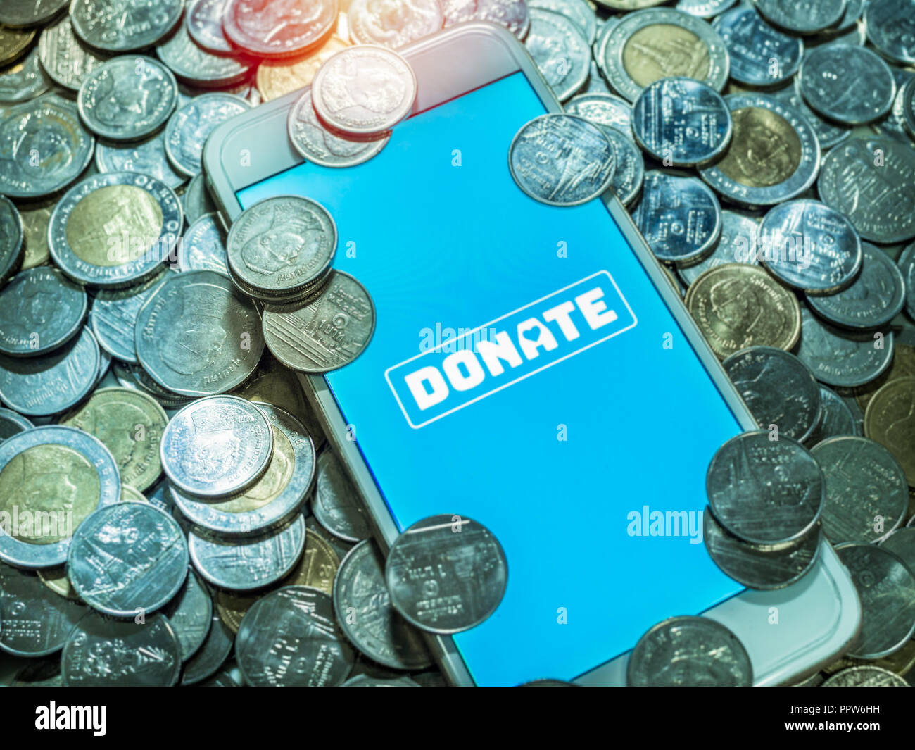 Donate icon button on blue screen on white mobile phone on coins Thai ...