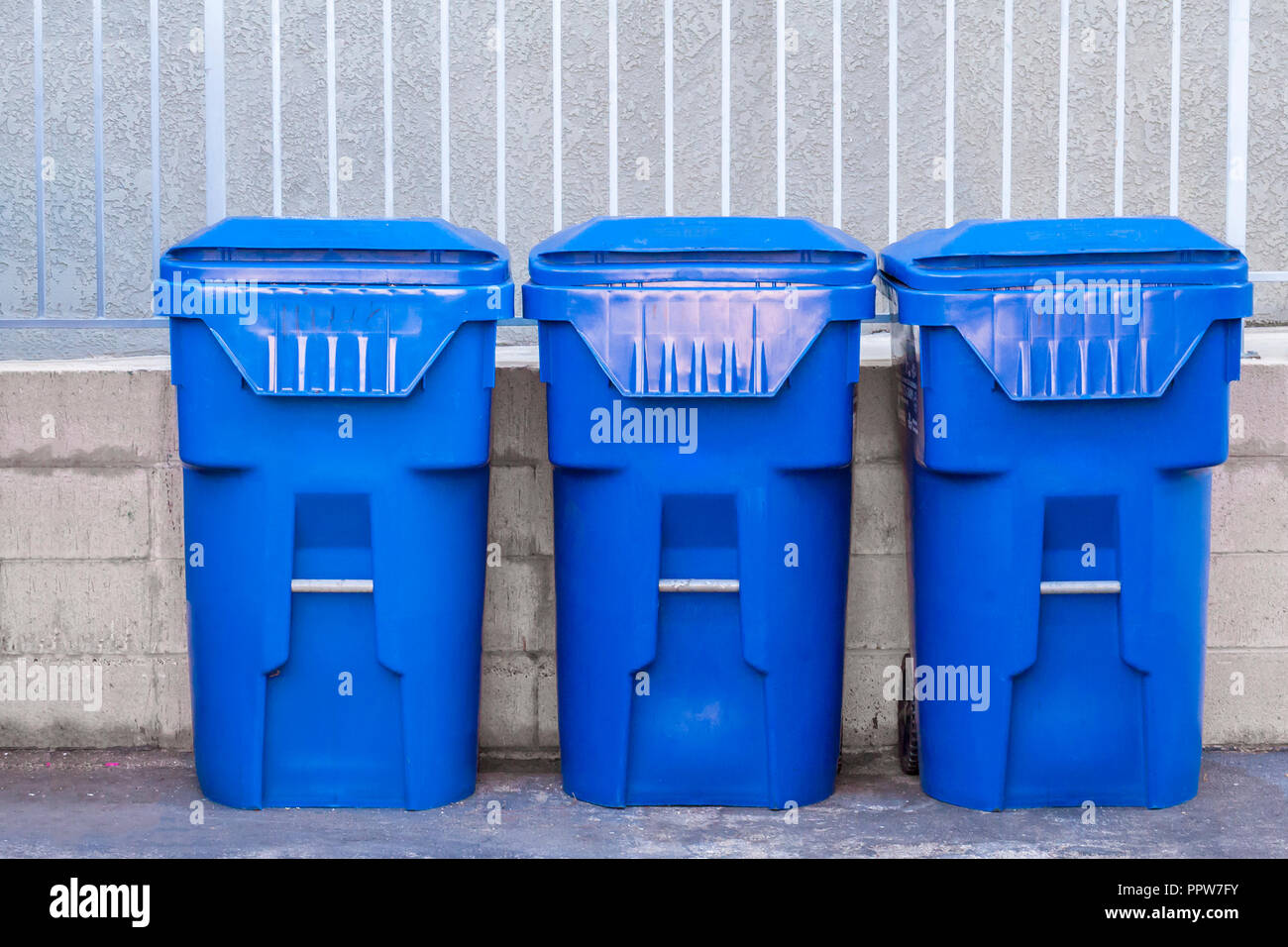 Blue trash bins against a wall Stock Photo - Alamy
