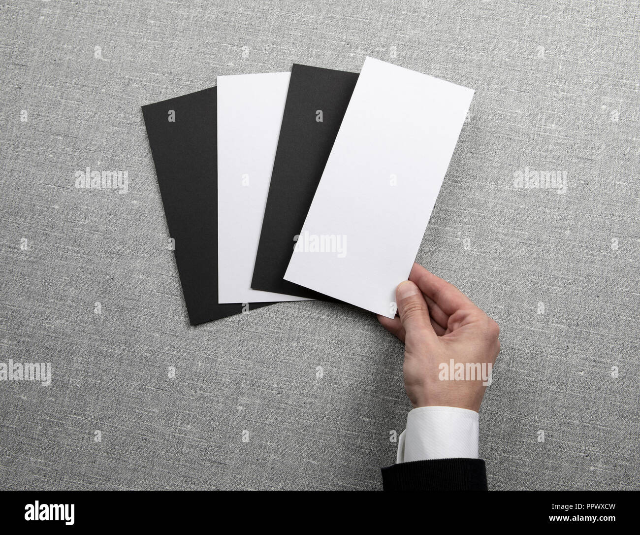 Mens hand holding empty white and black flyers on light gray background ...