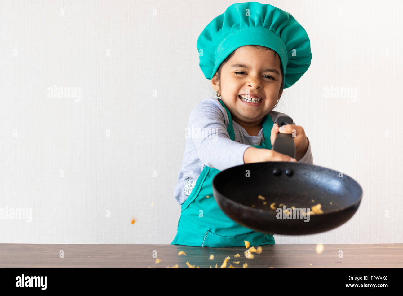 Cute little girl cooking with her frying pan in the kitchen Stock Photo ...