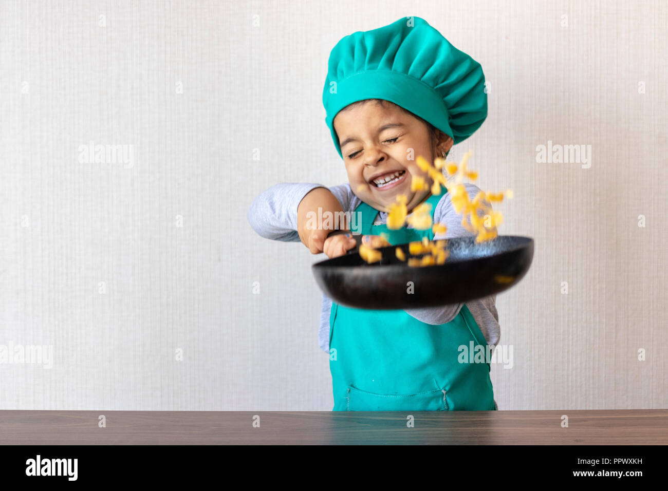 Cute little girl cooking with her frying pan in the kitchen Stock Photo ...