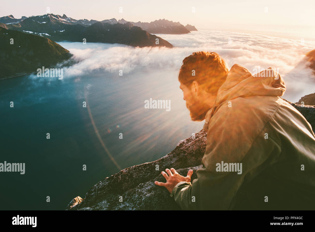 Man on the edge cliff above sea gaze into abyss lying down traveling in mountains adventure ...