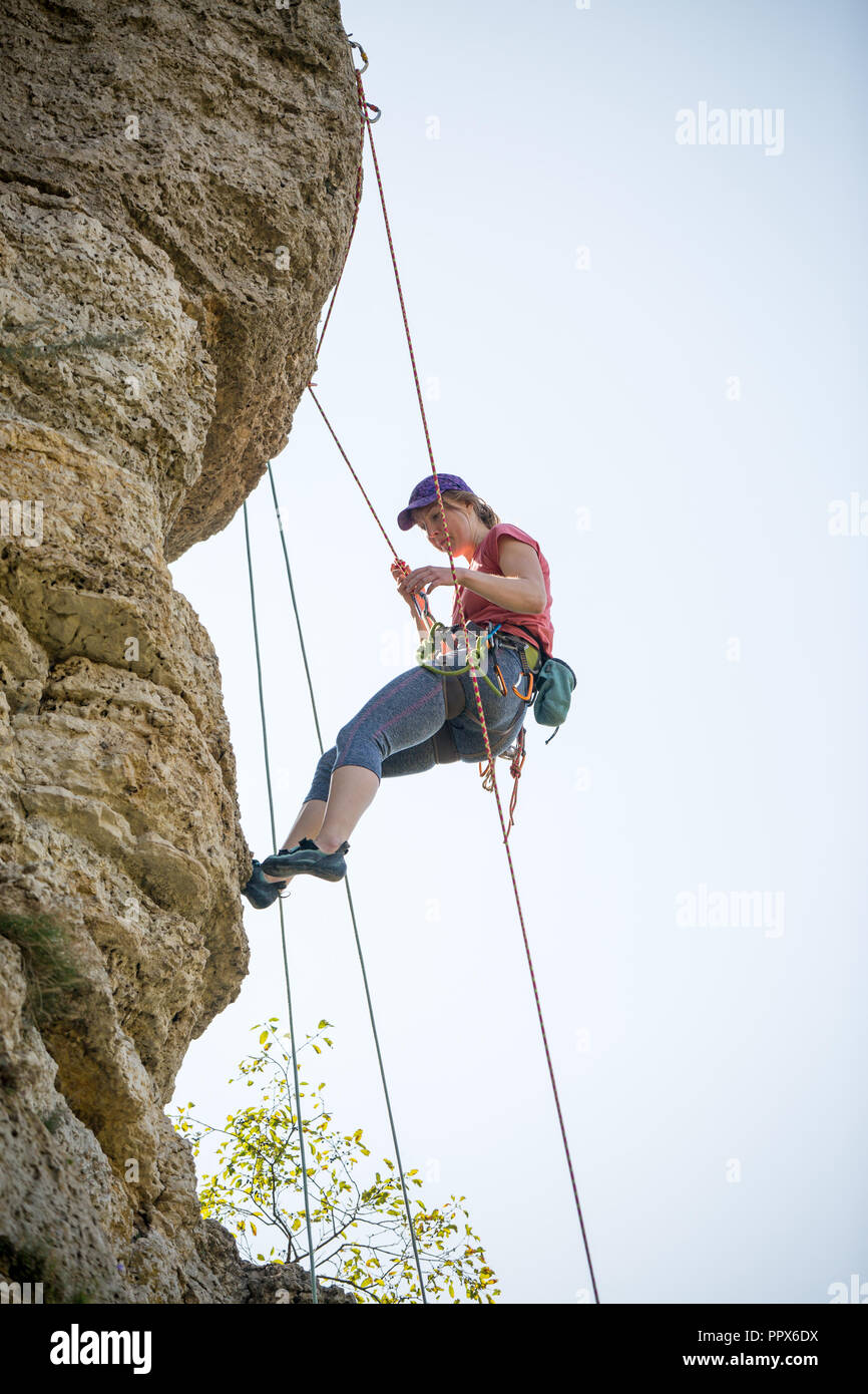Photo of athlete woman in helmet clambering over rock Stock Photo - Alamy