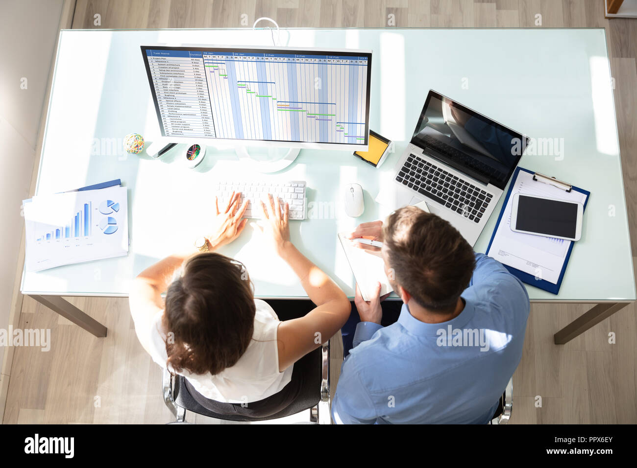 Overhead View Of Two Businesspeople Analyzing Gantt Chart On Computer ...
