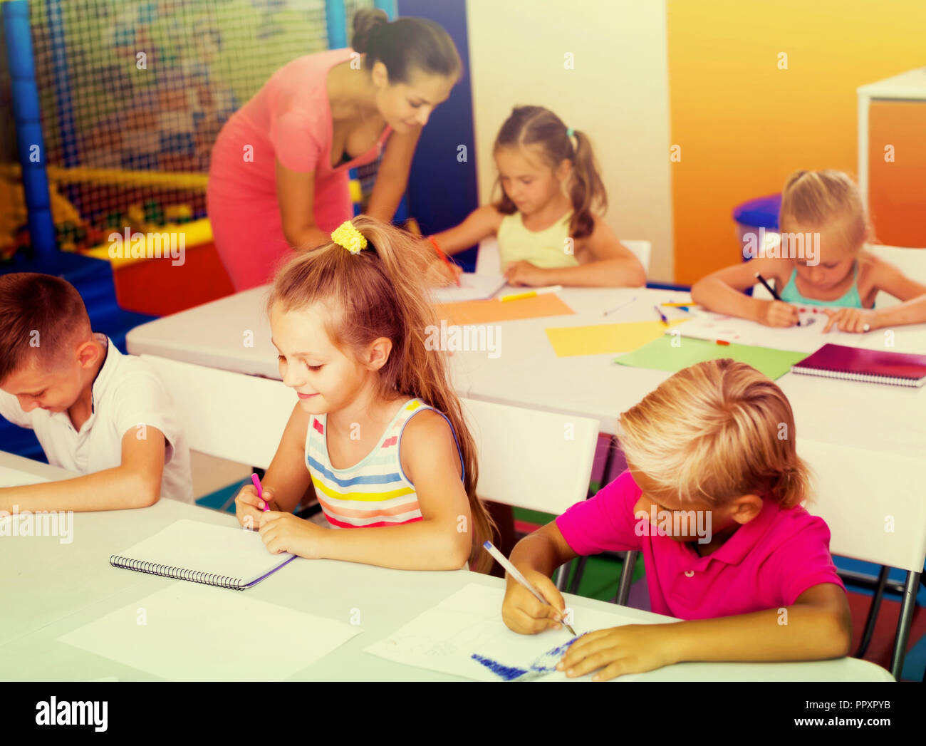 positive little children sitting together and studying in class at ...
