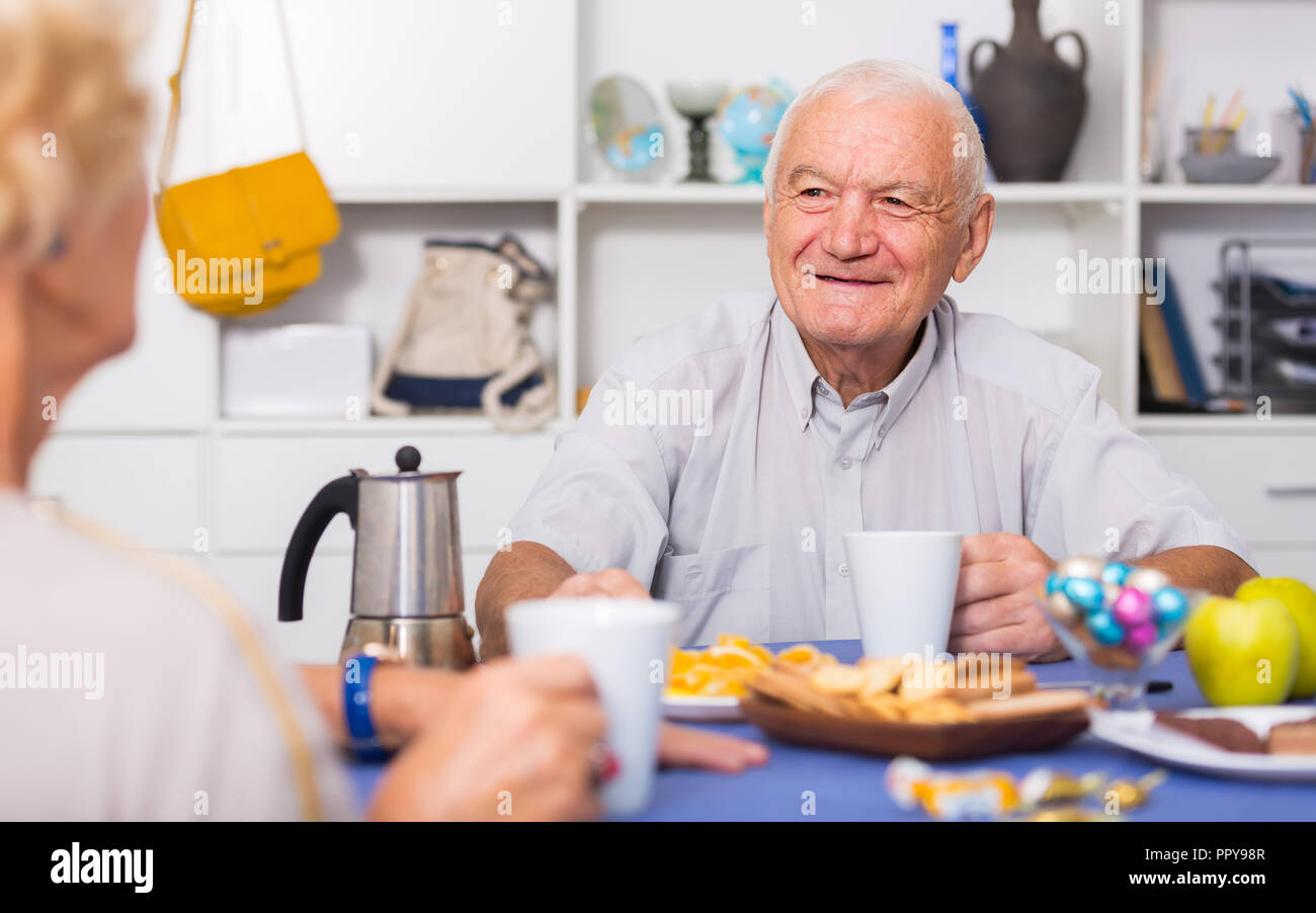 Happy senior man enjoying conversation with wife over cup of coffee at ...