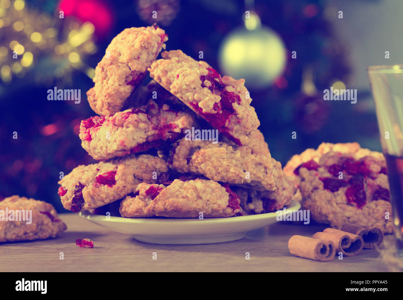 Oat cookies with berries on plate and glass of tea on blurry background ...