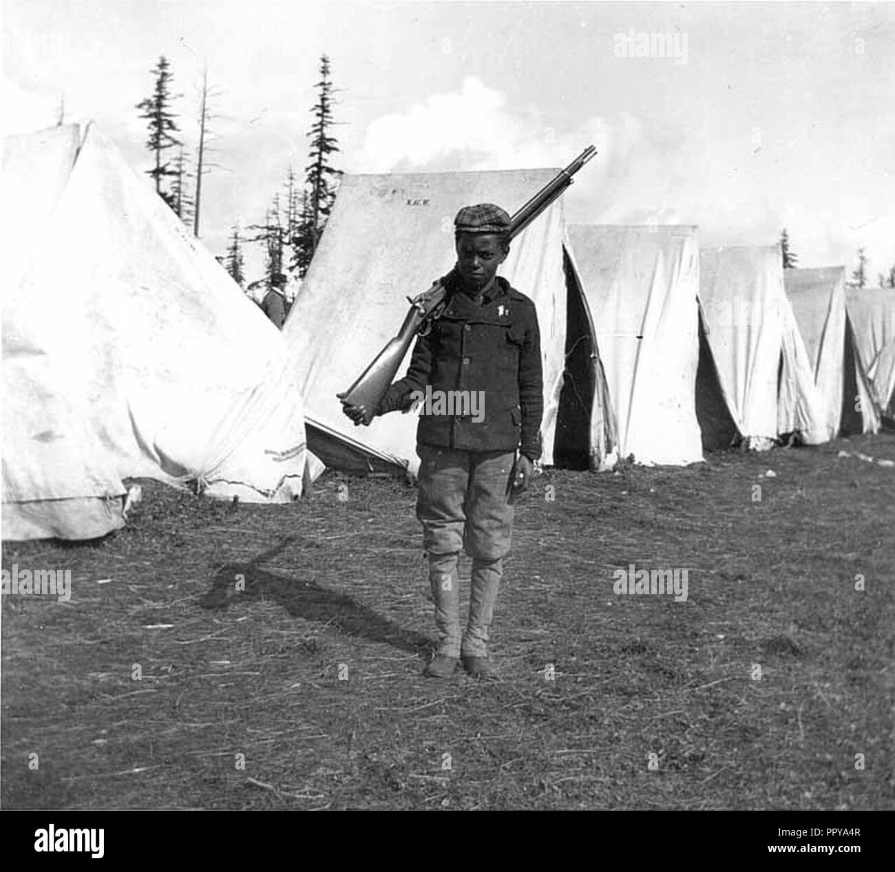 Boy dressed in military uniform with rifle at camp, Fort Lawton, May ...