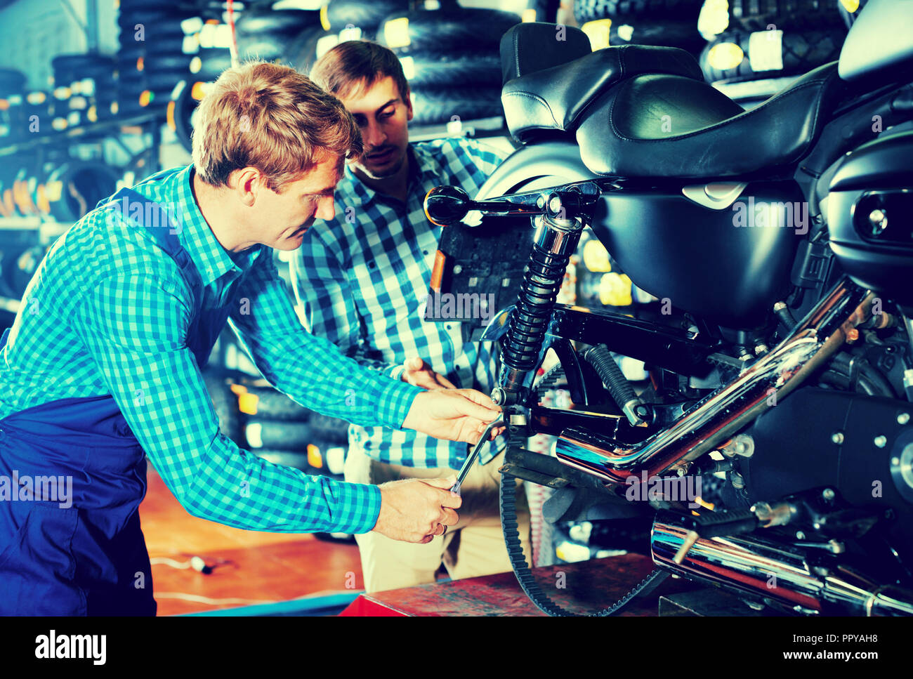 Positive male technician standing with customer in shop with ...