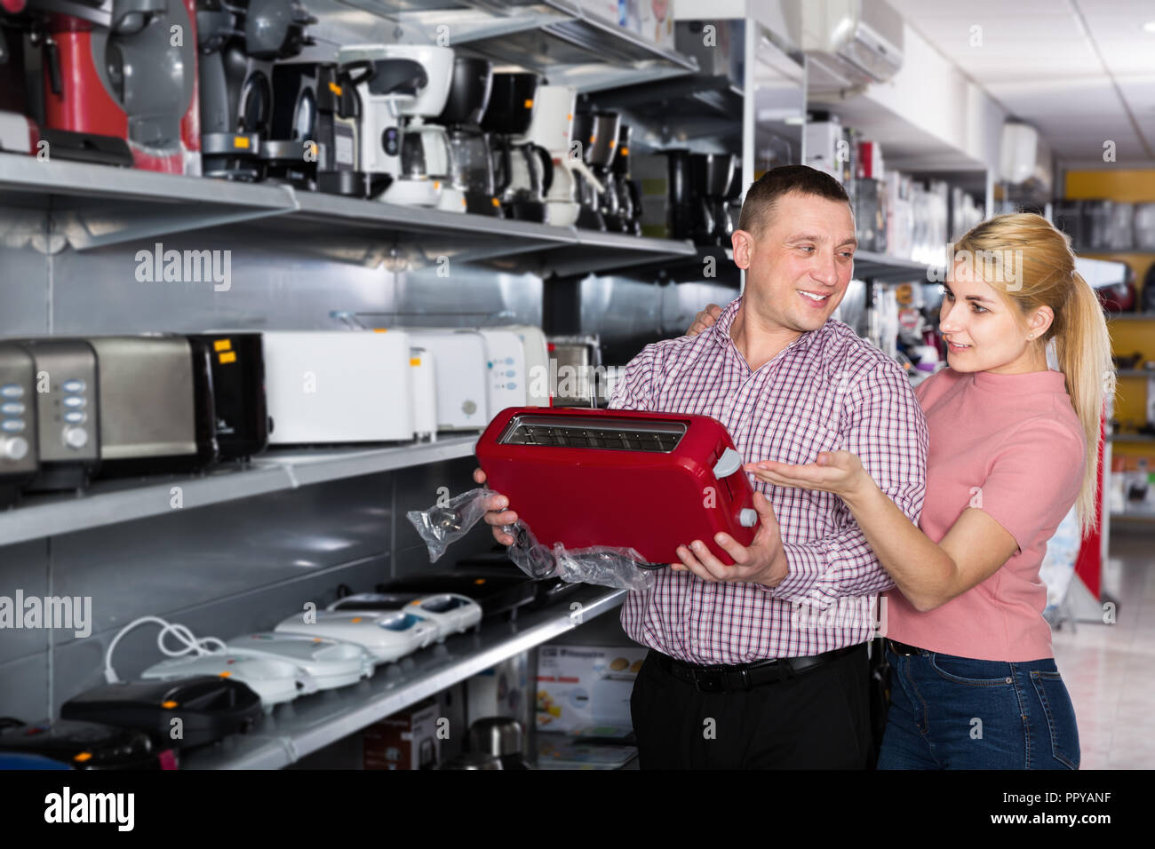 Positive couple choosing new kitchen toaster at household shop Stock ...