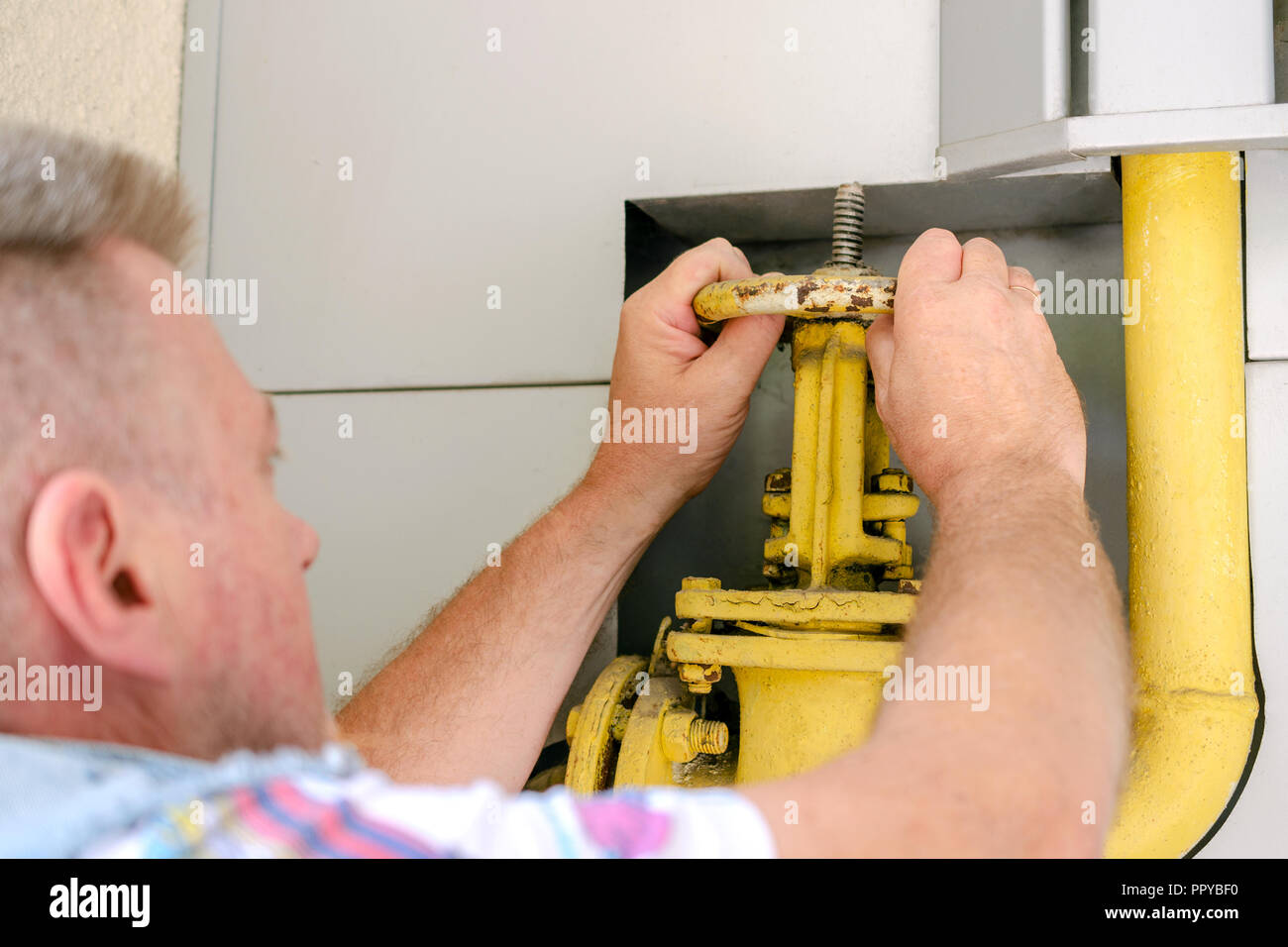 Man opens or closes on a gas pipe valve to control gases entering the ...