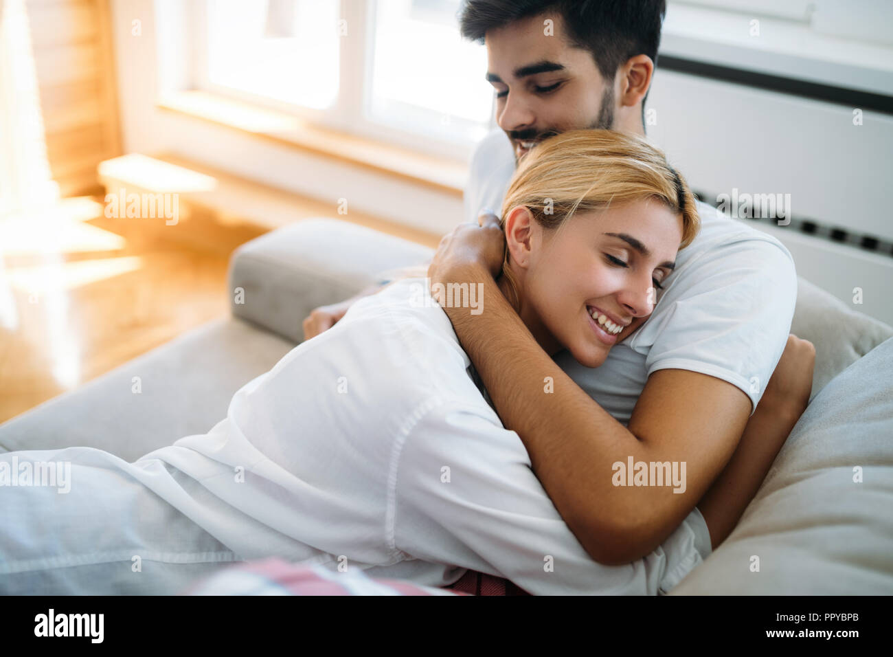 Cute couple hugging and smiling in their home Stock Photo - Alamy