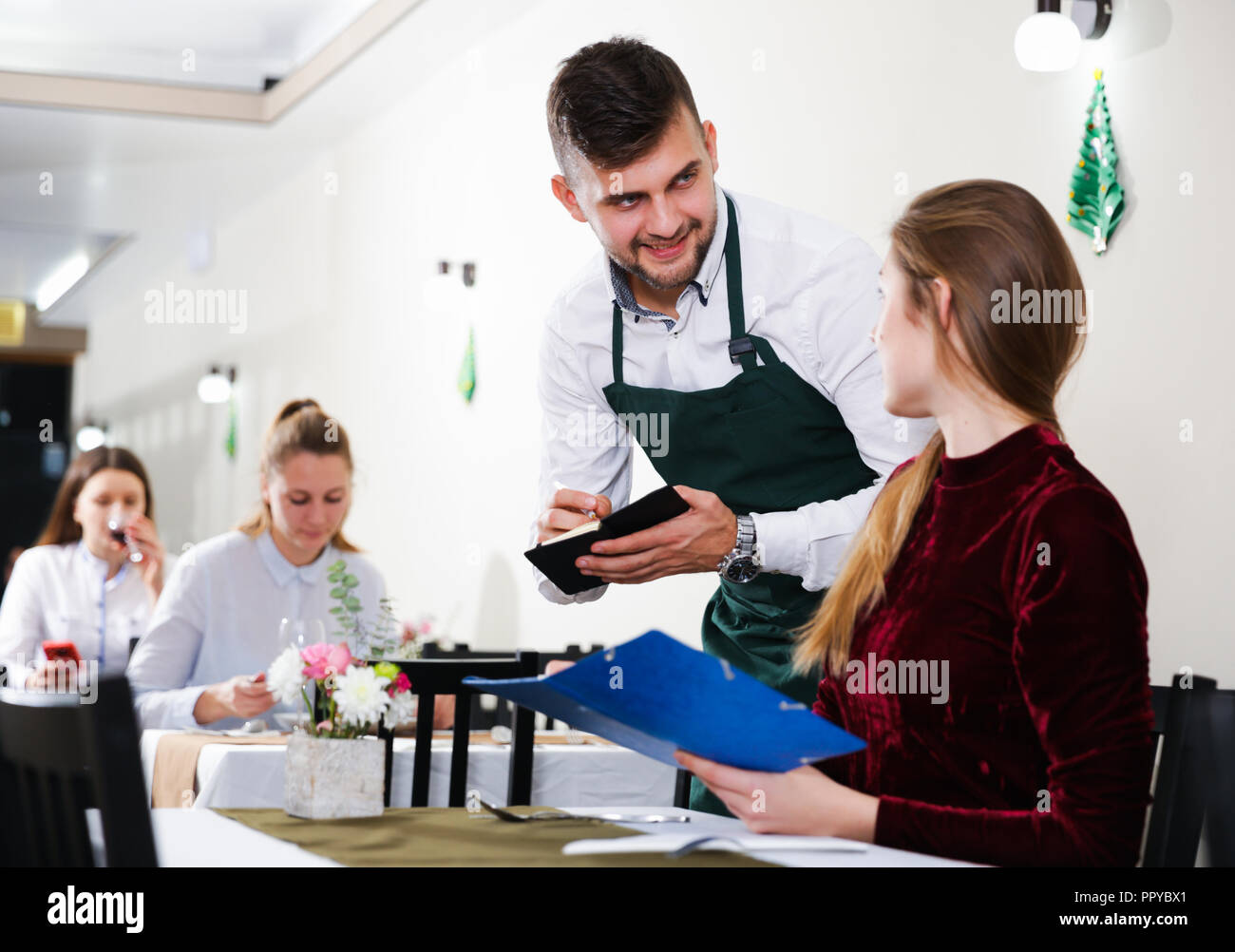 Waiter is taking order from young female in restaurante indoor Stock ...