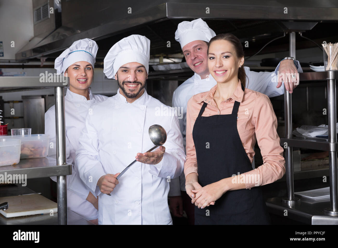 Team of restaurant staff posing together in modern professional kitchen ...