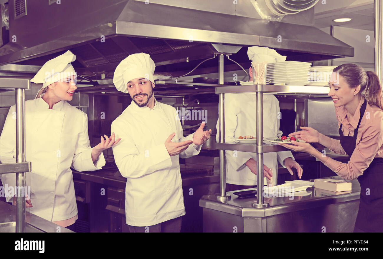 Staff of restaurant with adult head chef working together in kitchen ...