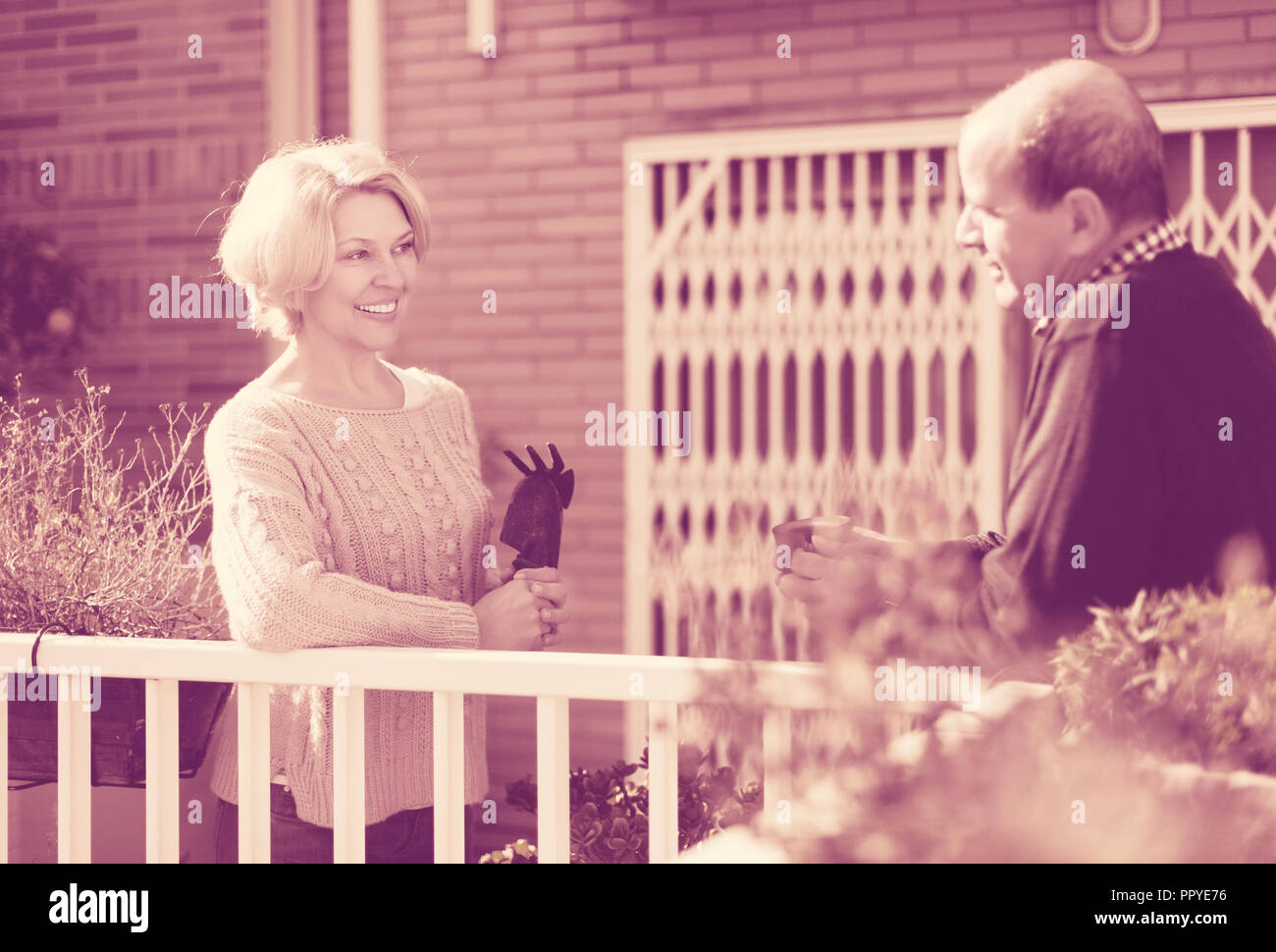 Mature smiling woman talking with male neighbor at balcon Stock Photo ...