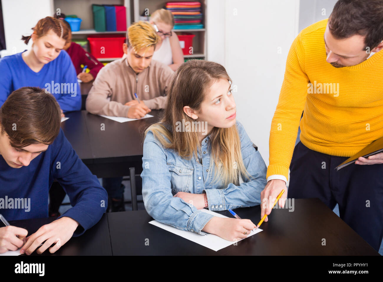 Teacher explaining difficult problem to student during test at class ...
