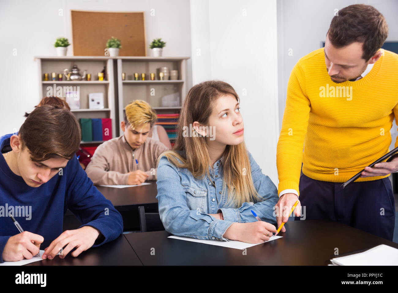 Teacher explaining difficult problem to student during test at the ...