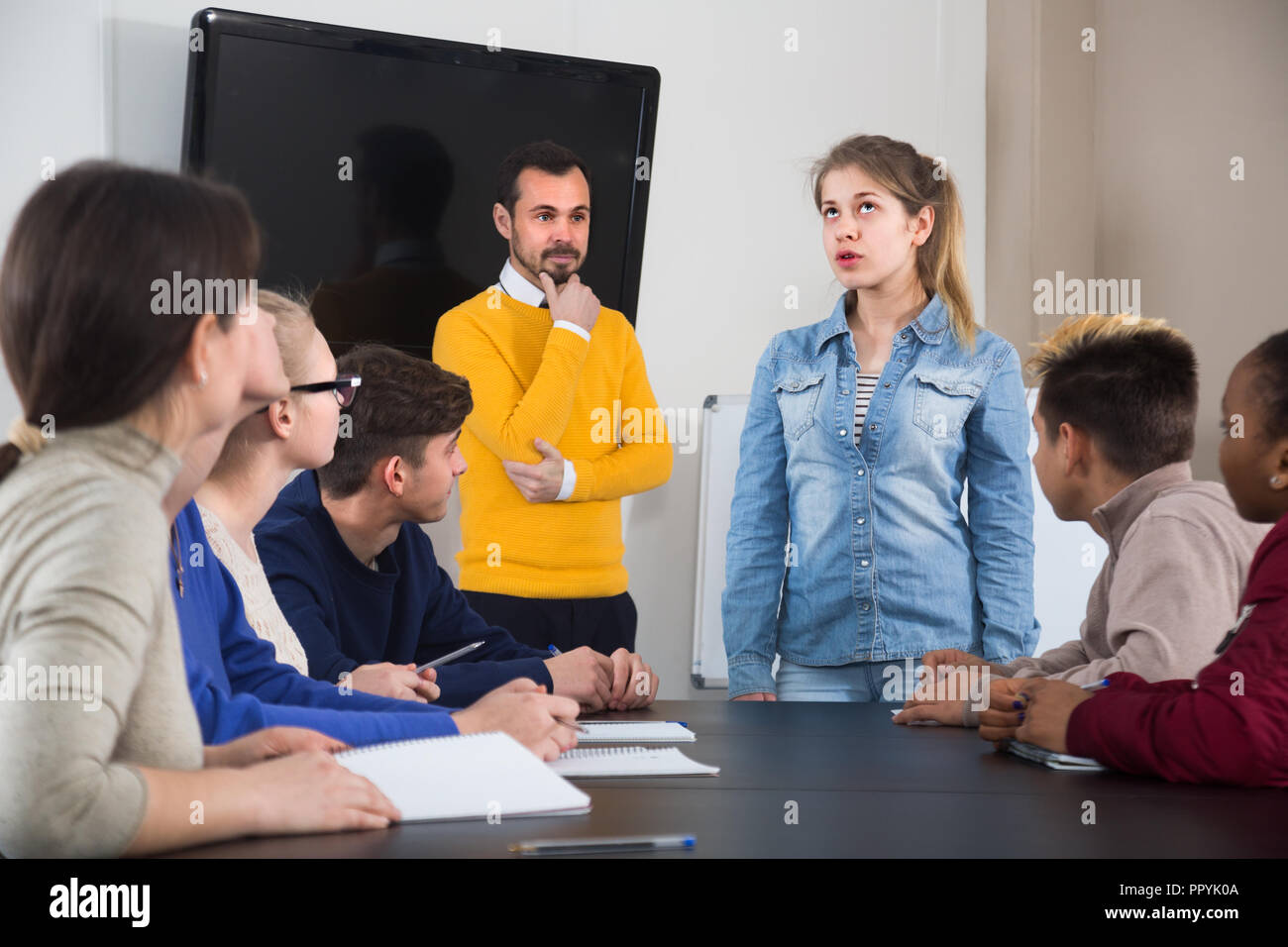 Female student is answering to teacher’s question at writing board in ...
