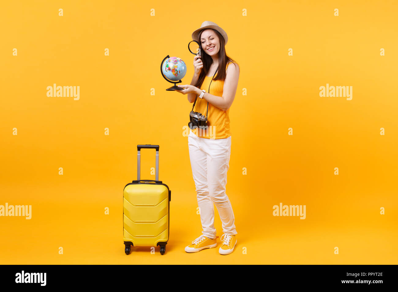 Tourist woman in summer hat looking through loupe on globe, choice ...