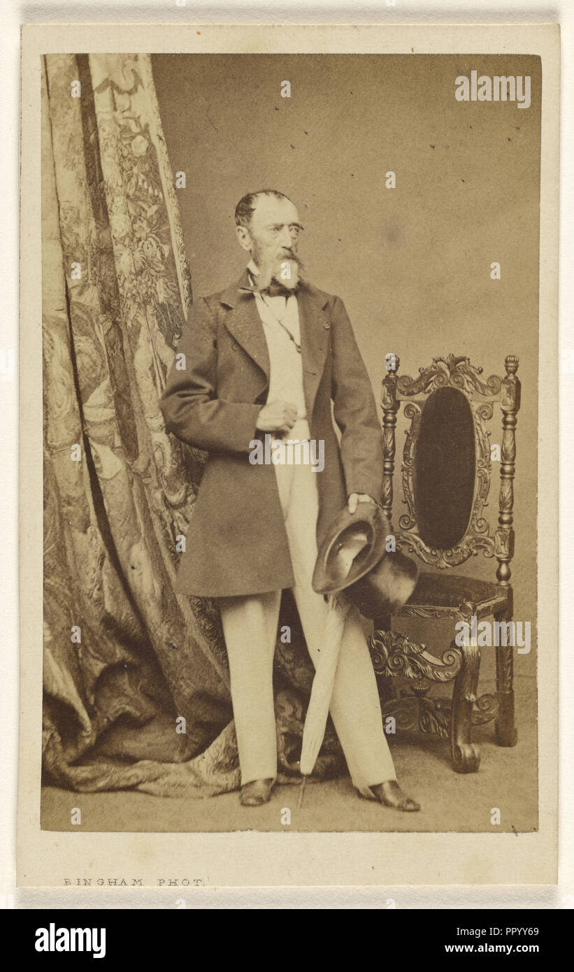 man with full white beard, standing, holding a top hat and umbrella in ...