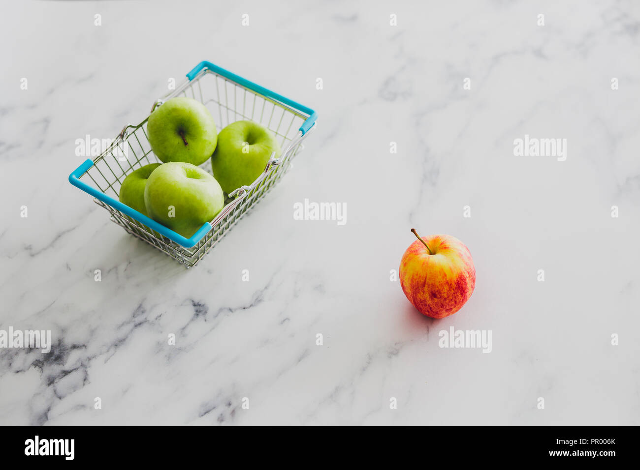 grocery store mini shopping basket with one single red apple among ...
