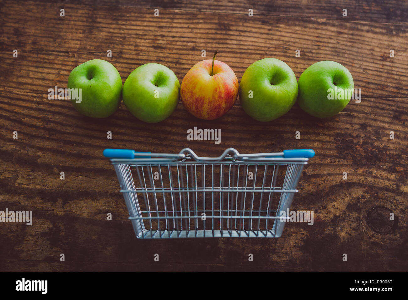 grocery store mini shopping basket with one single red apple among ...
