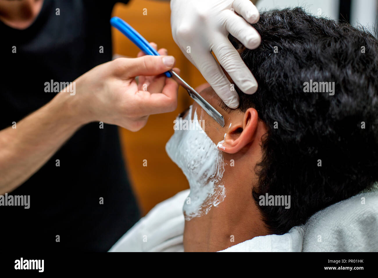 the young man is being shaved with a straight razor in a barbershop ...