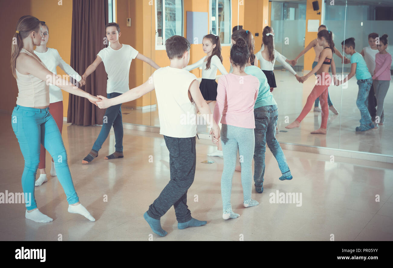 Group of tweens exercising folk dance, forming circle with female ...