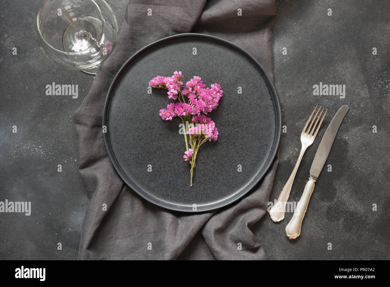 Elegance modern place setting with pink wildflowers on black table. Top ...