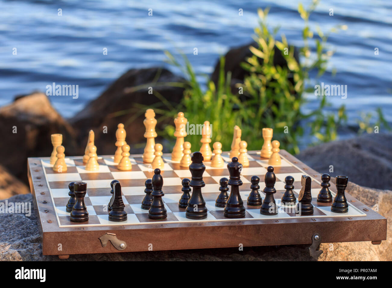 Chess board with chess pieces on rock with river embankment background ...