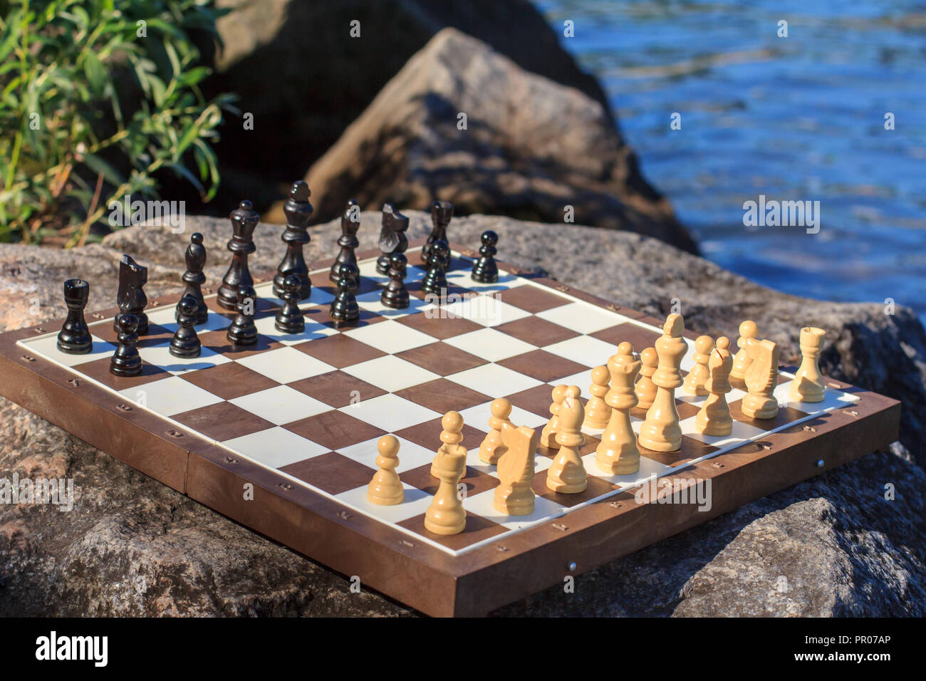 Chess board with chess pieces on rock with river embankment background ...