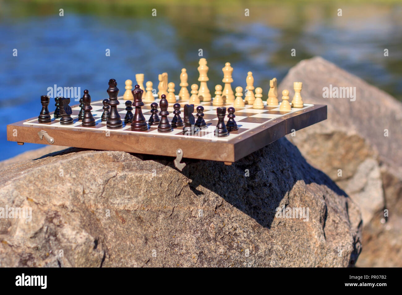 Chess board with chess pieces on rock with river embankment background ...