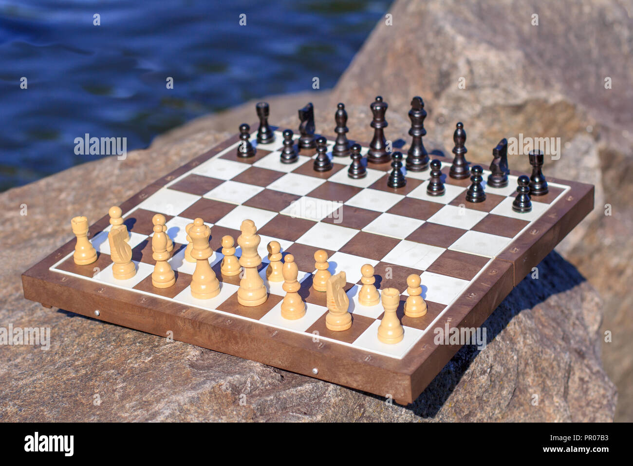 Chess board with chess pieces on rock with river embankment background ...