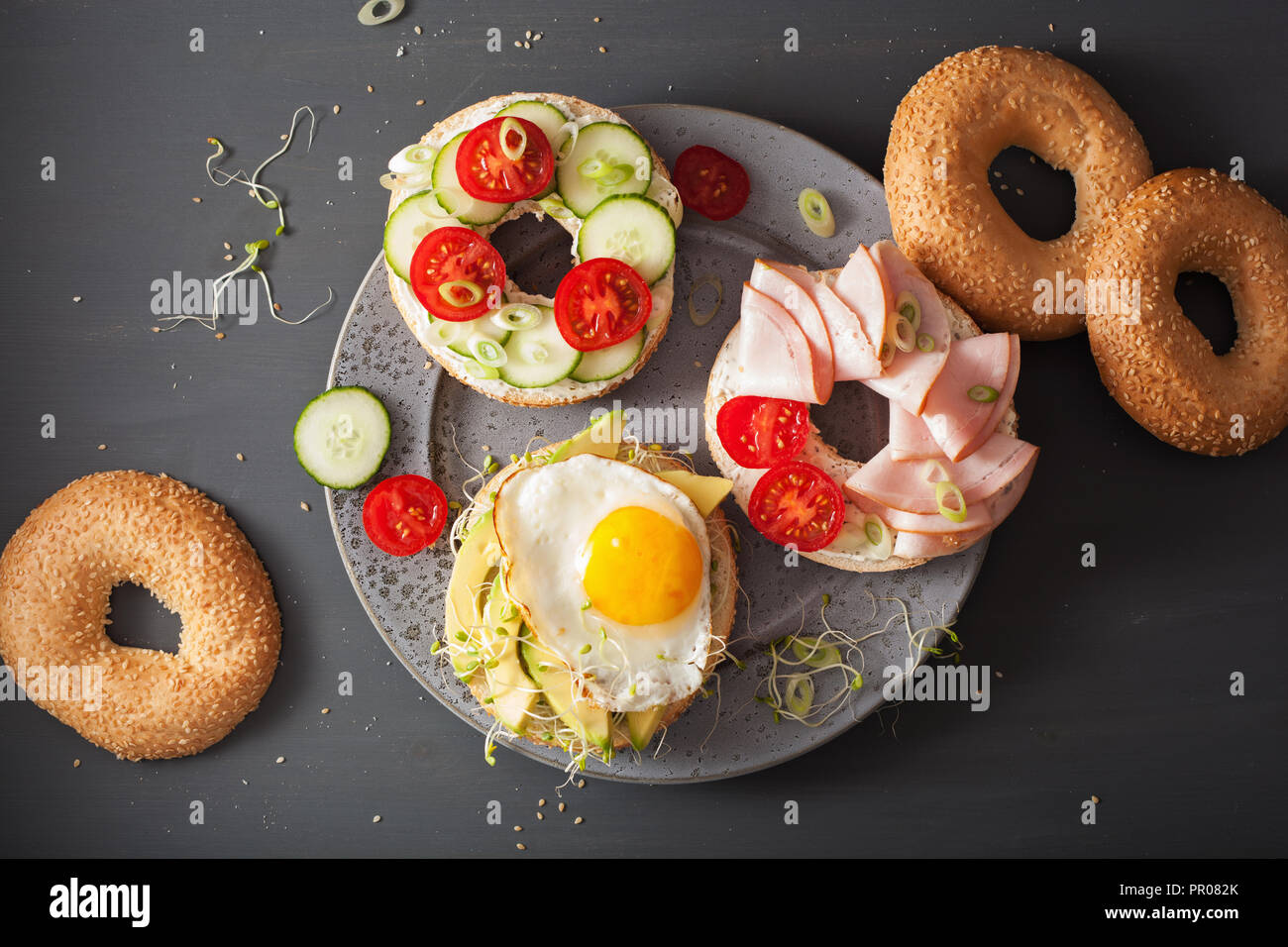 variety of sandwiches on bagels: egg, avocado, ham, tomato, soft cheese ...